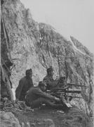 Vier Soldaten mit Gewehren und Maschinengewehren in einer Stellung